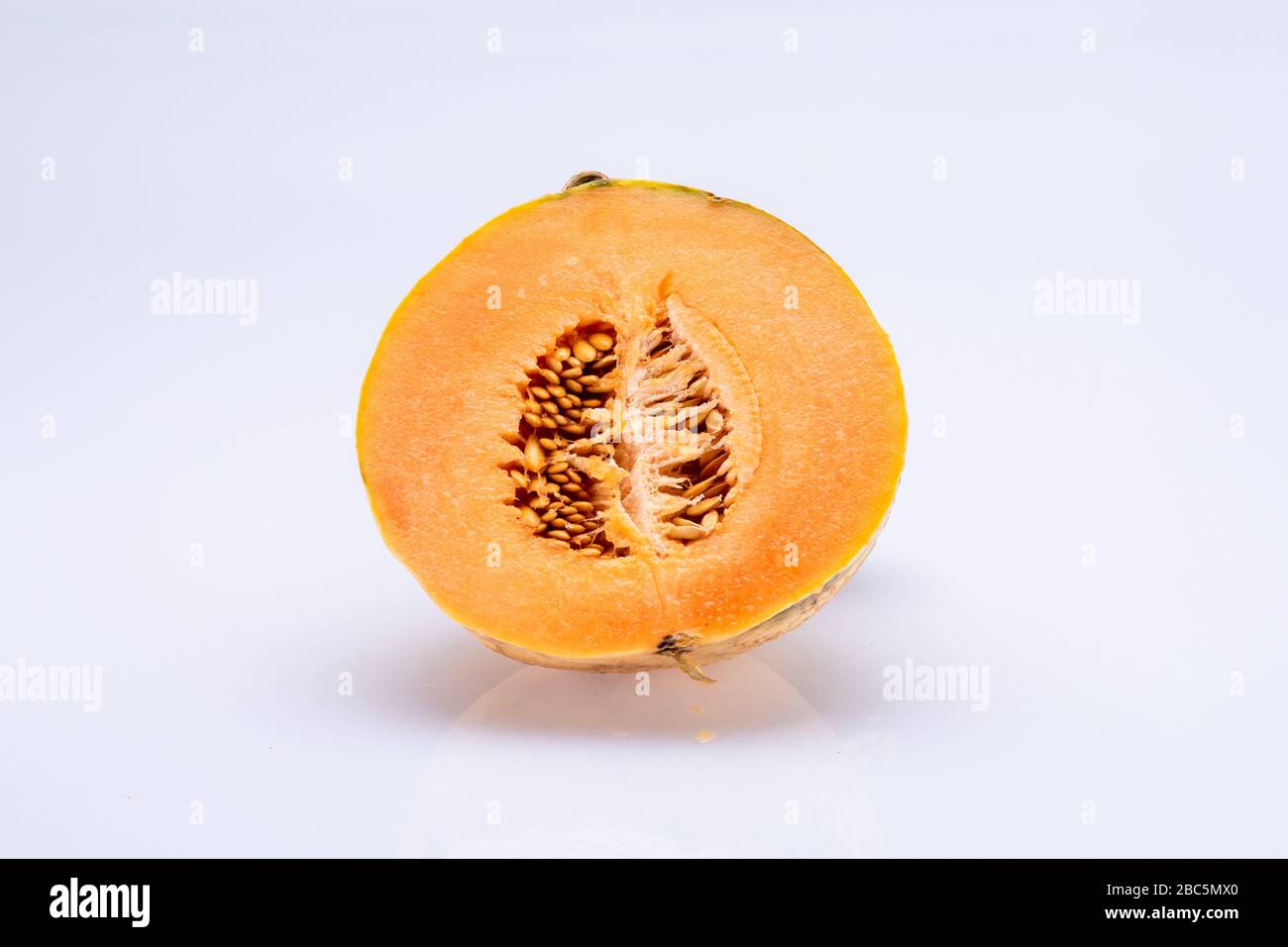 Melon sliced in half with visible seeds inside isolated in front of a ...