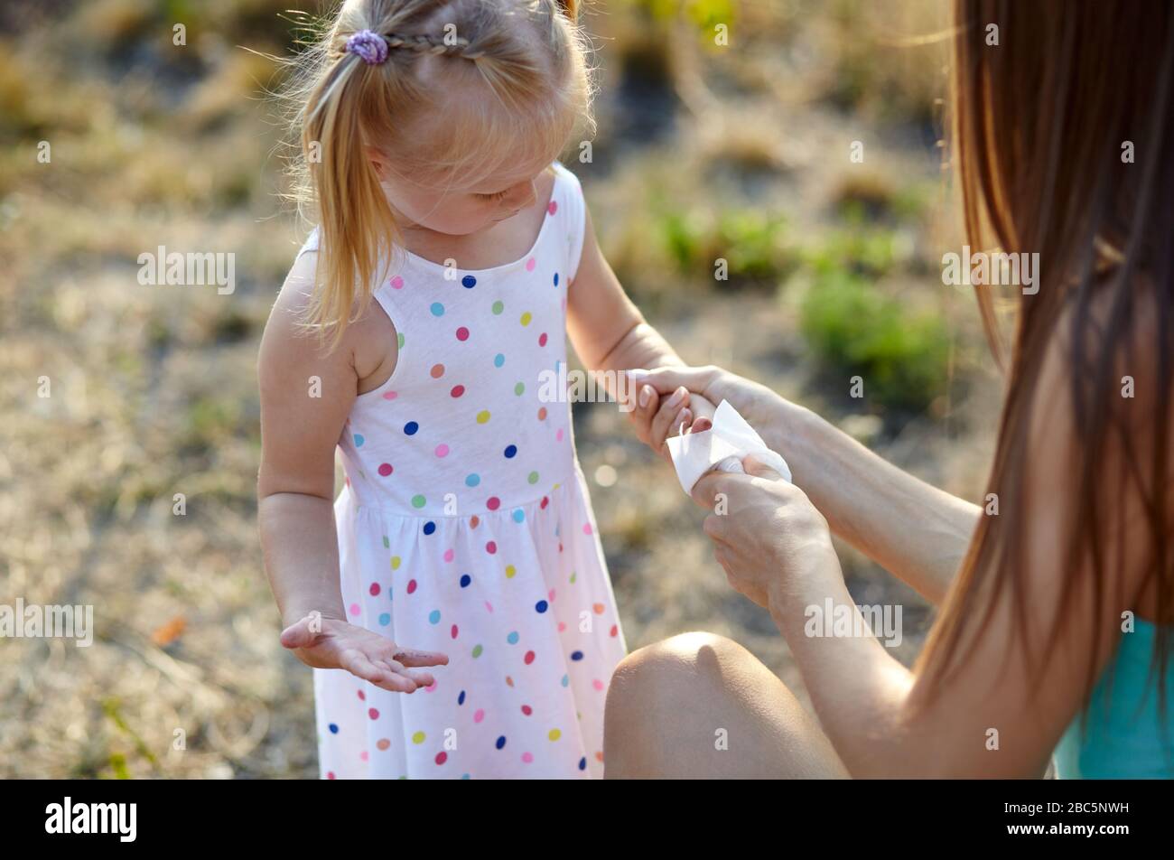 Mom wipes her daughter’s palm with a damp napkin. Mom cares for her ...