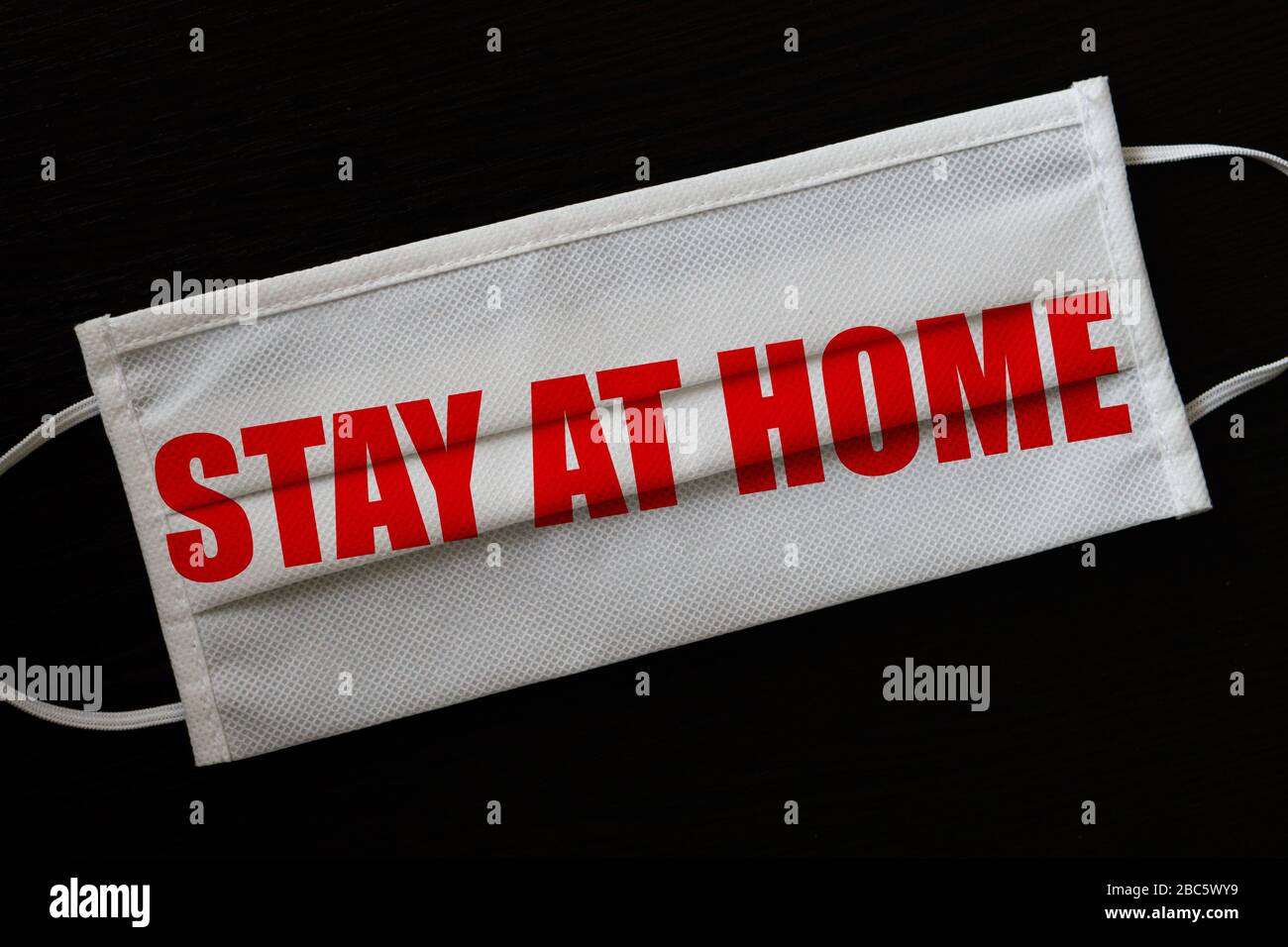 Medical Face Mask and Stay At Home Text Isolated on black. The ...