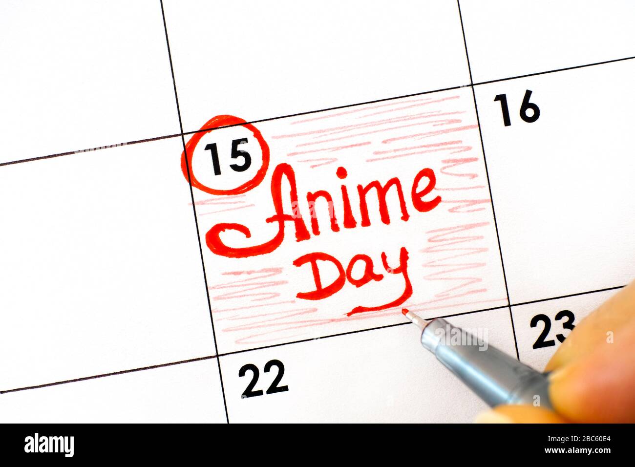 Woman fingers with pen writing reminder Anime Day in calendar. April 15 ...