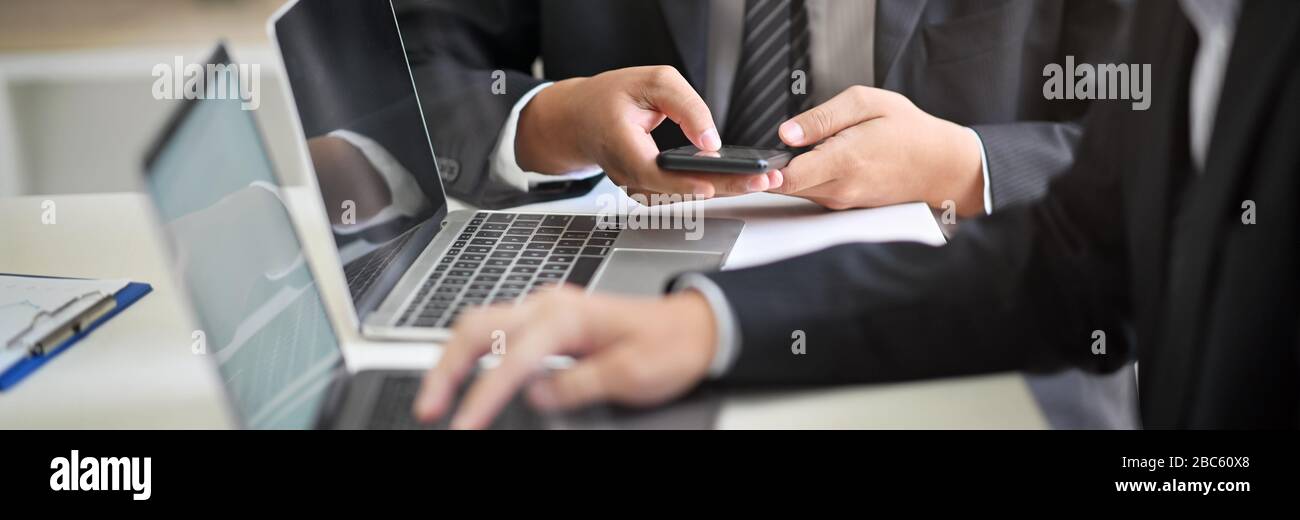 Side view of two male entrepreneurs consulting on their business with ...