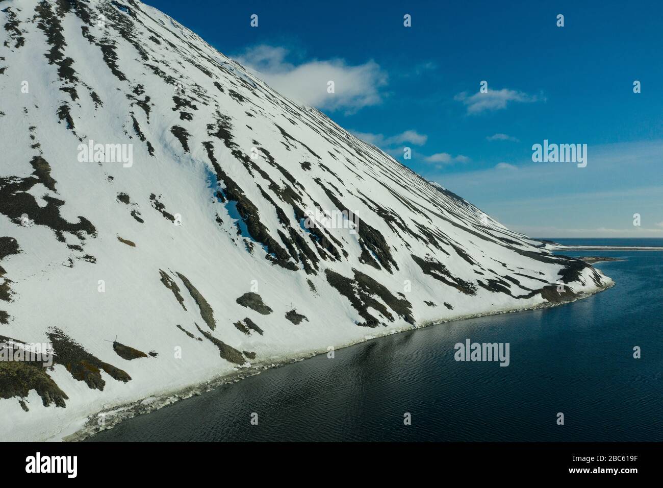 The mountainous sea coast covered with snow in a sunny weather. Place ...