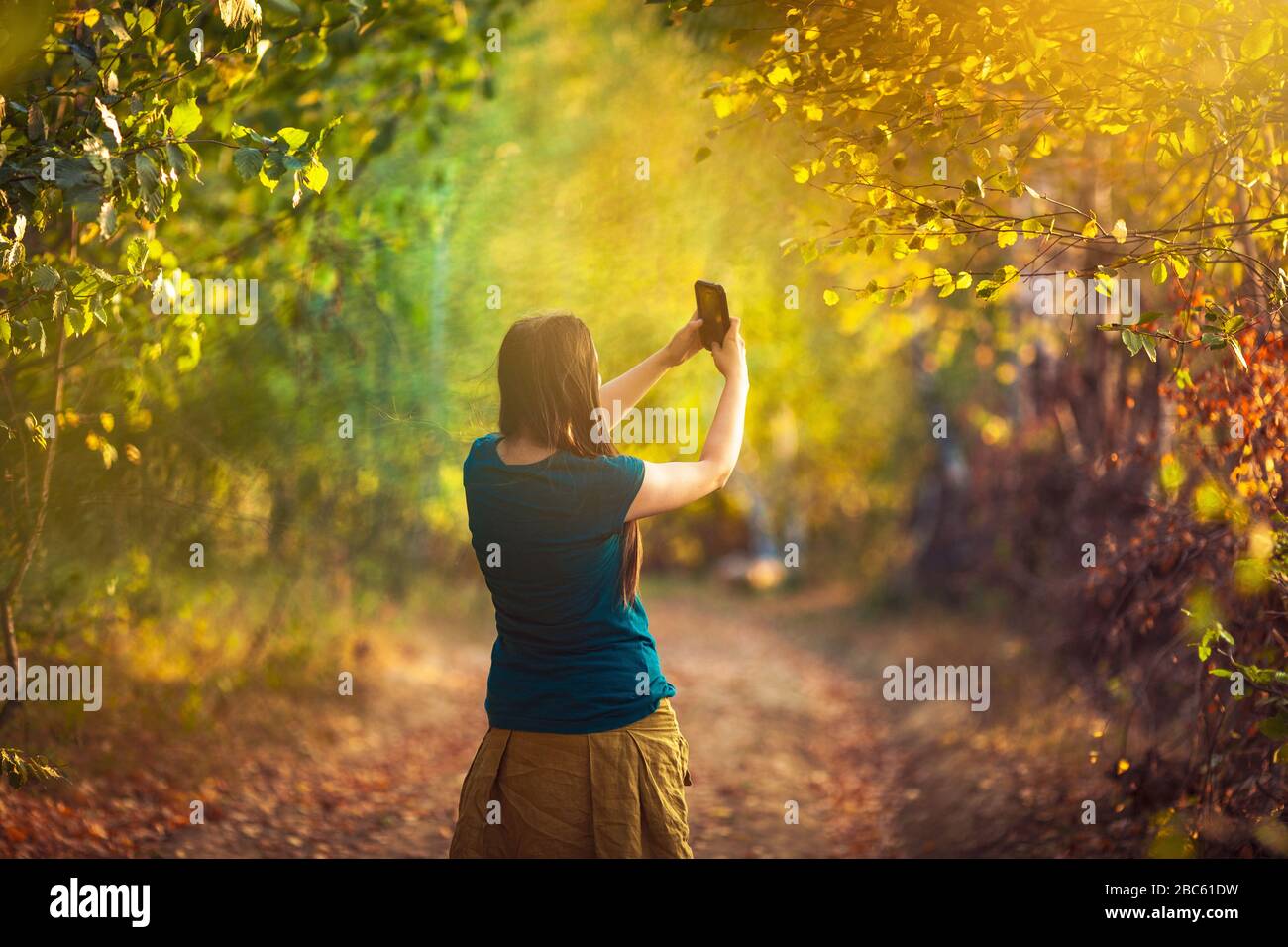 Girl taking photo using mobile phone, early autumn colors Stock Photo ...