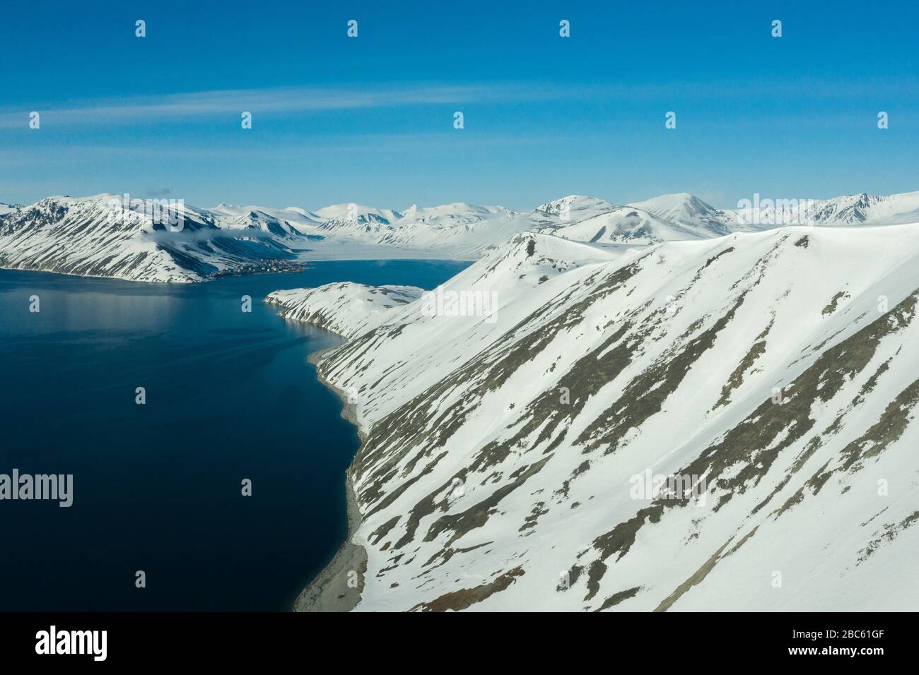 The mountainous sea coast covered with snow in a sunny weather. Place ...