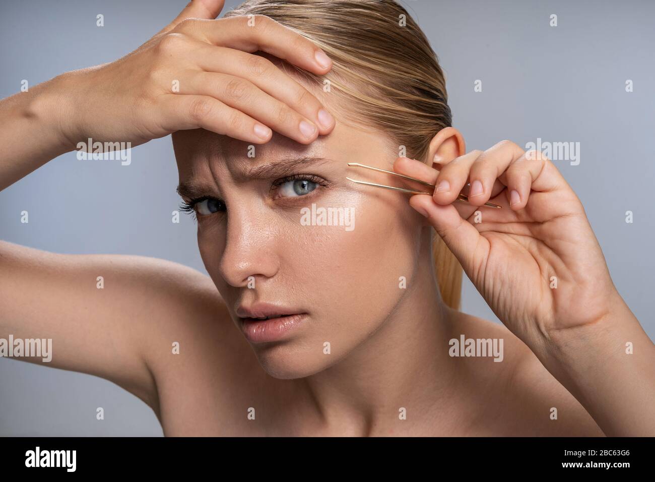 Attentive young female person pinching her eyebrows Stock Photo - Alamy