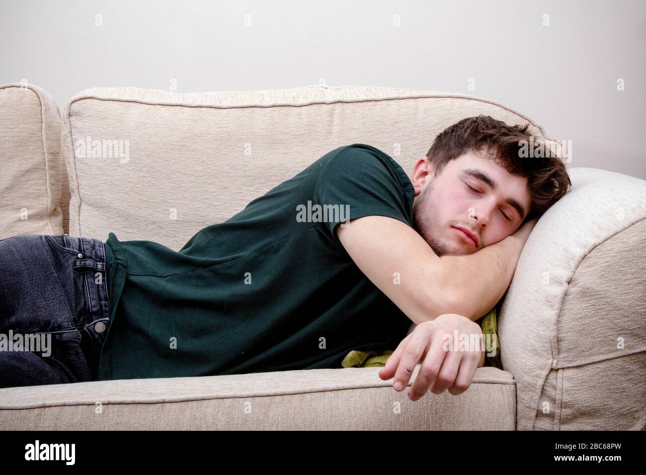 A young adult man asleep on a sofa Stock Photo - Alamy