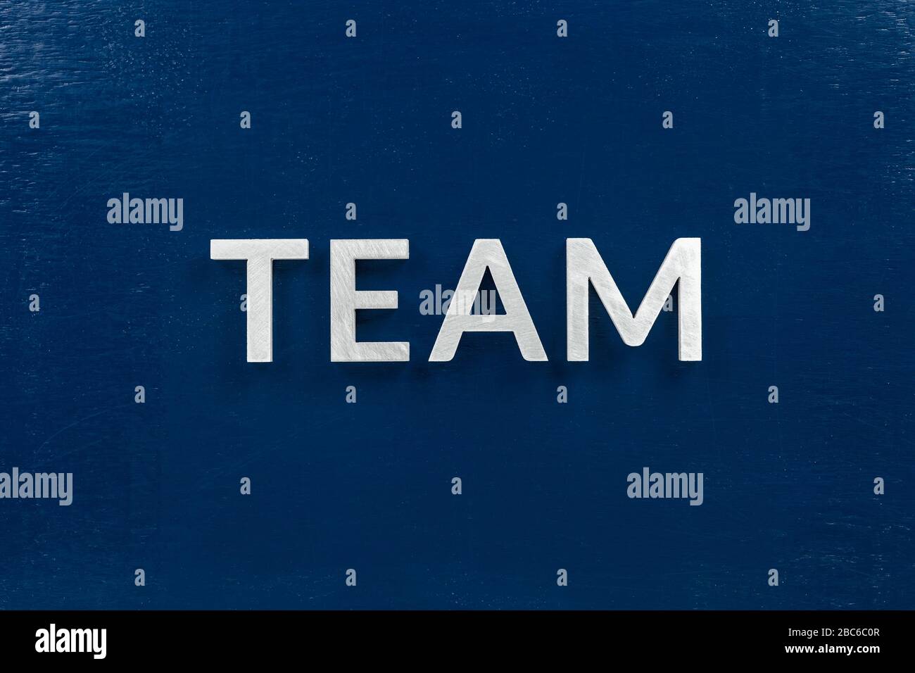 the word team laid with aluminium letters on dark-blue flat background ...