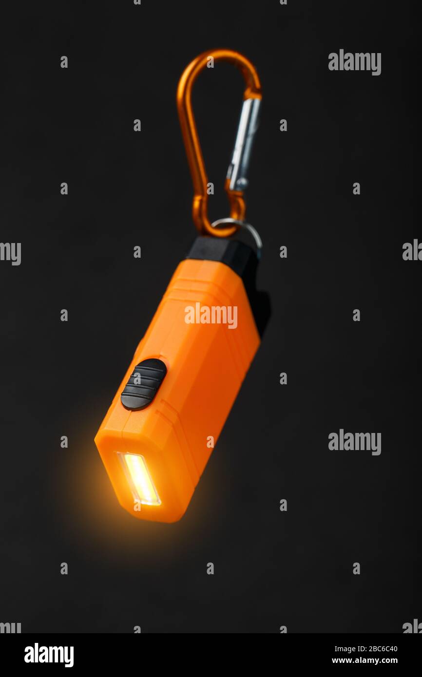 Orange led Flashlight with a carabiner on a black background. LED ...