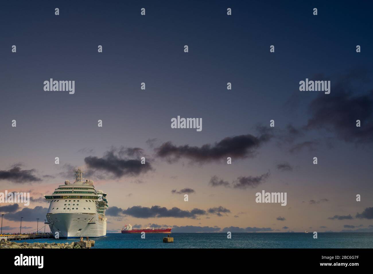 Red Freighter Beyond Cruise Ship at Sundown Stock Photo - Alamy