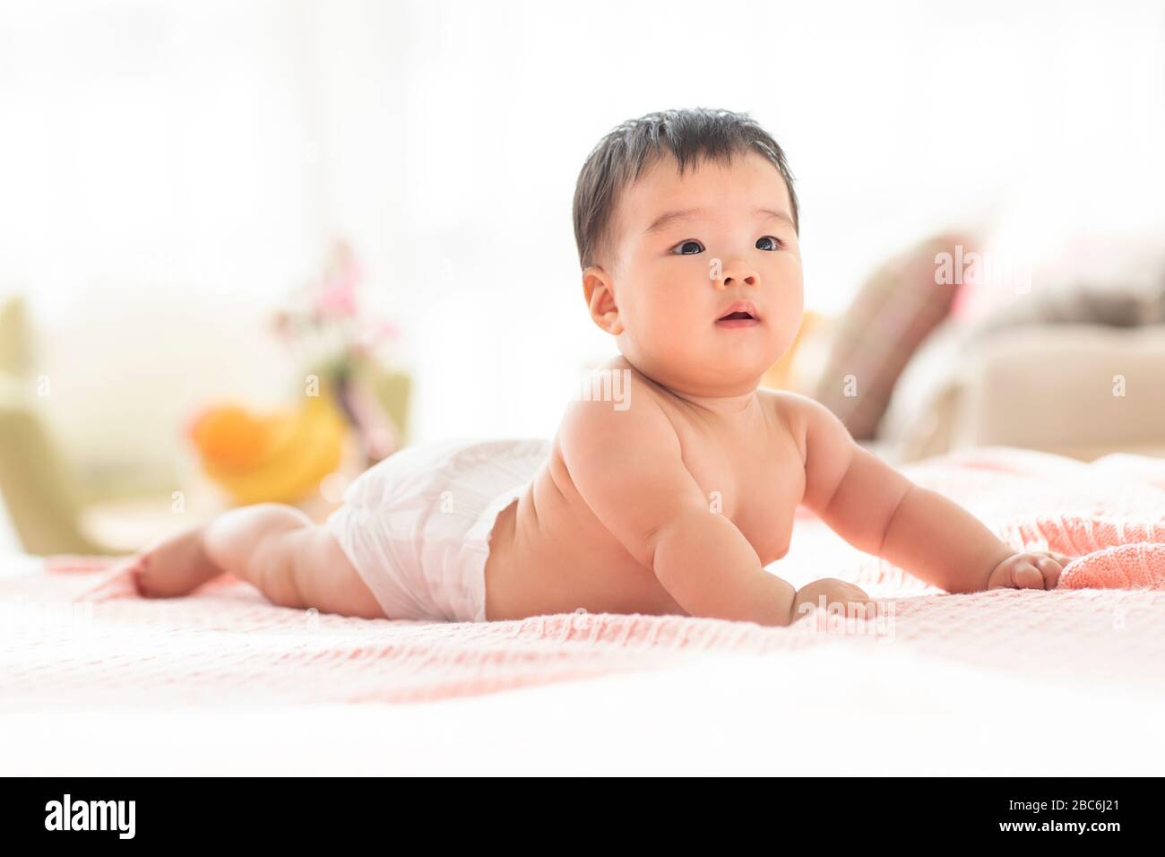 Little Chinese baby lying on front in bed Stock Photo - Alamy