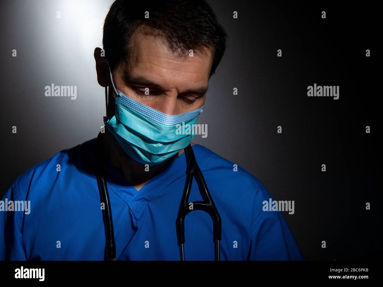 Worried / sad male doctor, with his head bowed / looking downward ...