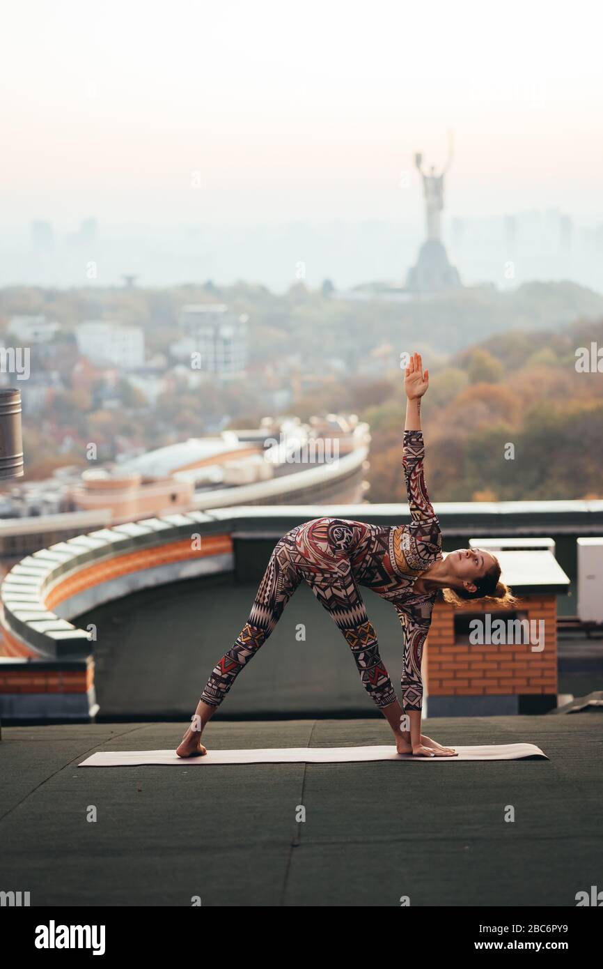 Woman doing yoga on the roof of a skyscraper in big city Stock Photo ...