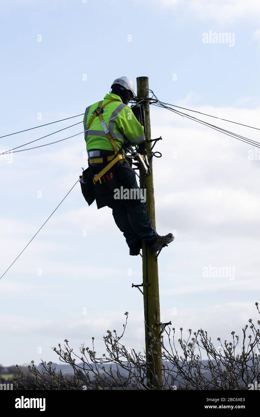 Telecom field engineer climbing a telegraph pole and carrying out ...