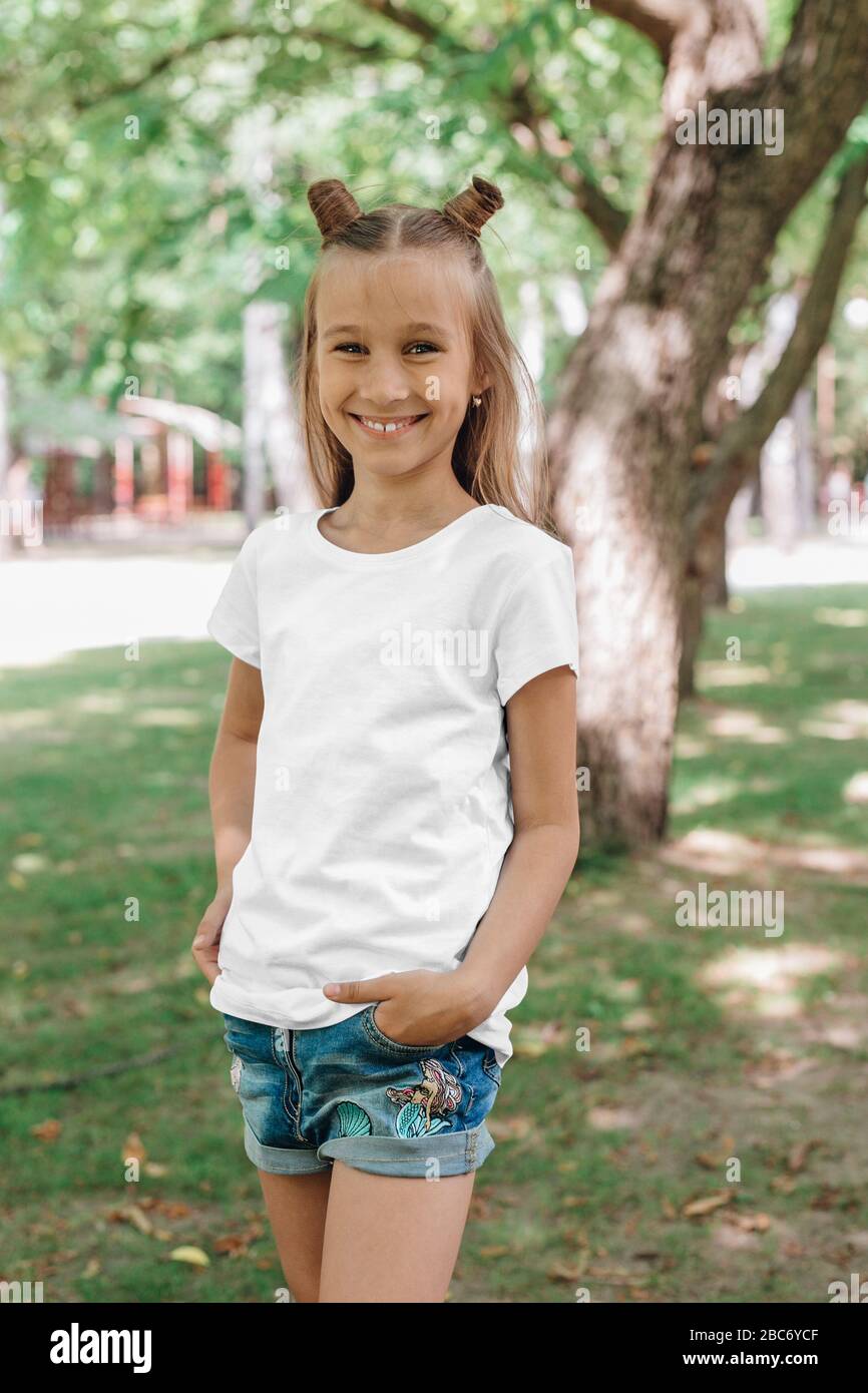 portrait of a little happy girl in a white T-shirt in park Stock Photo ...
