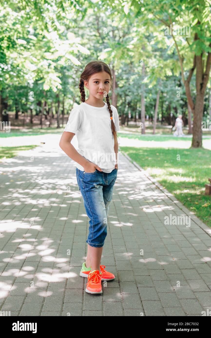 little smiling girl model in white shirt posing in park Stock Photo - Alamy