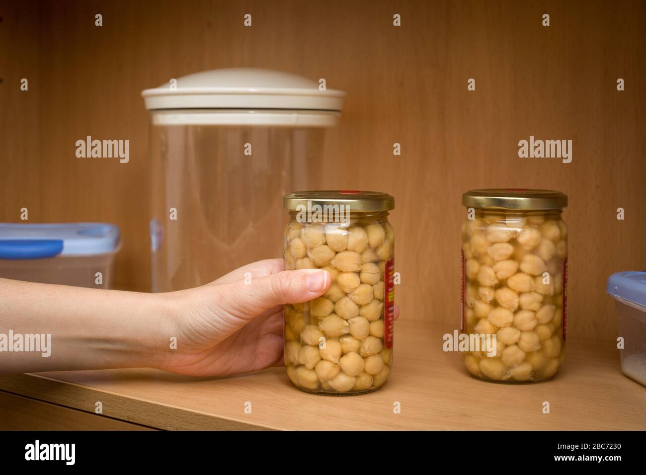 woman picking up a pot of chickpeas from the kitchen pantry Stock Photo ...