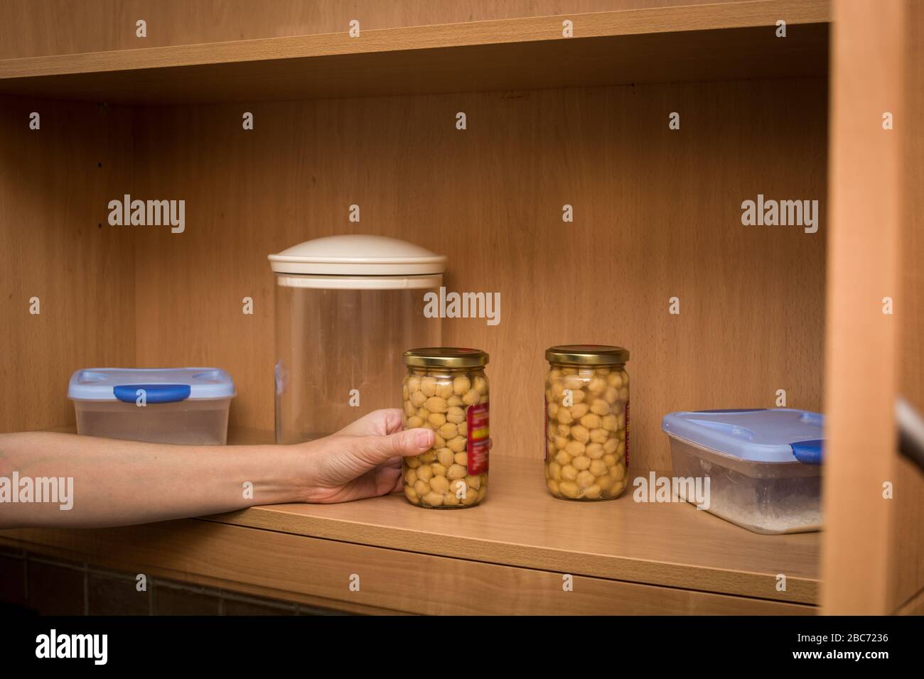 woman picking up a pot of chickpeas from the kitchen pantry Stock Photo ...