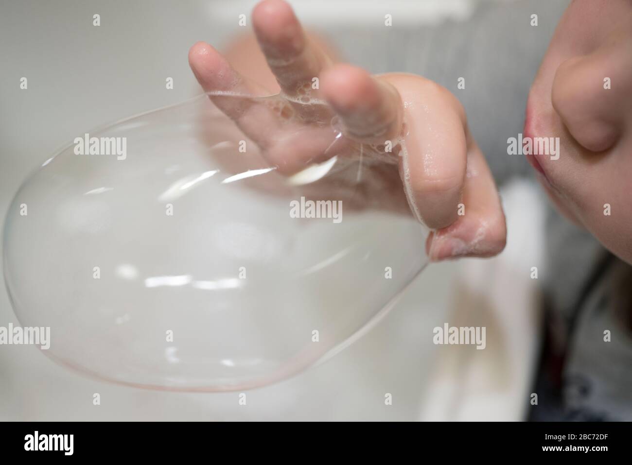 Young Boy Blowing a Soap Balloon Stock Photo - Alamy