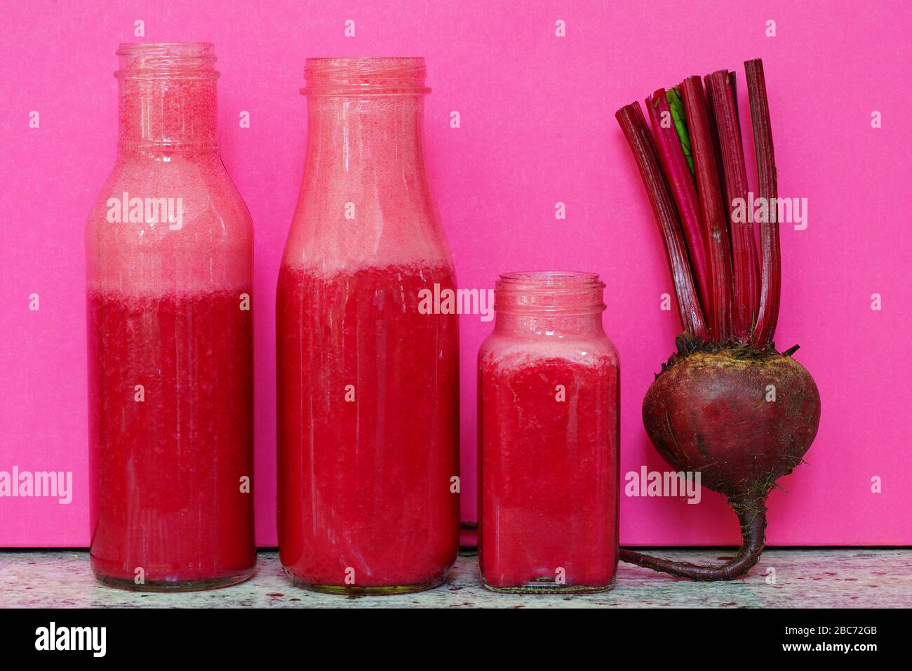 Glass bottles filled with colorful fresh homemade beet smoothies on a ...