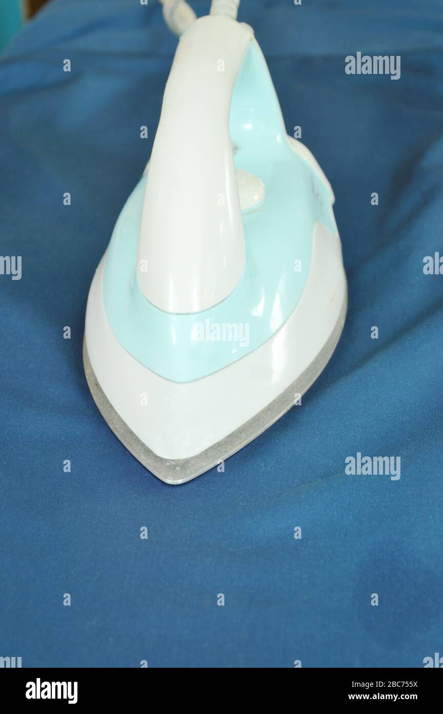 blue automatic electric iron pressing cloth on ironing board Stock ...