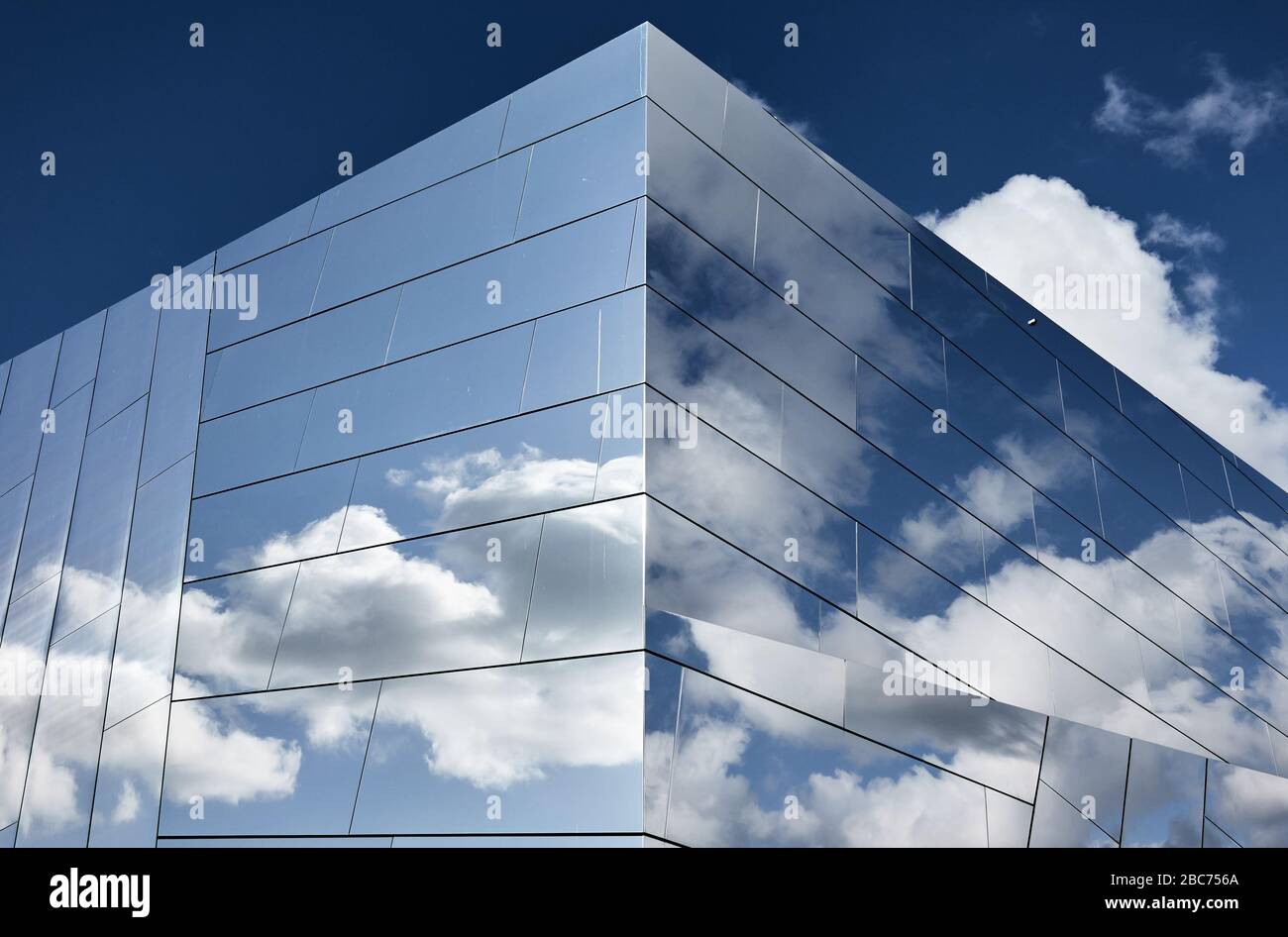Reflection of clouds and blue sky in the facade of a modern rectangular ...