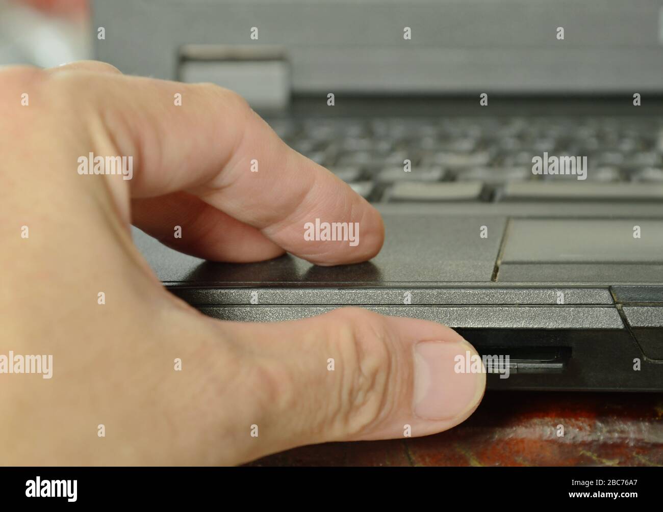 thumb pressing SD card put in computer notebook multimedia reader Stock ...