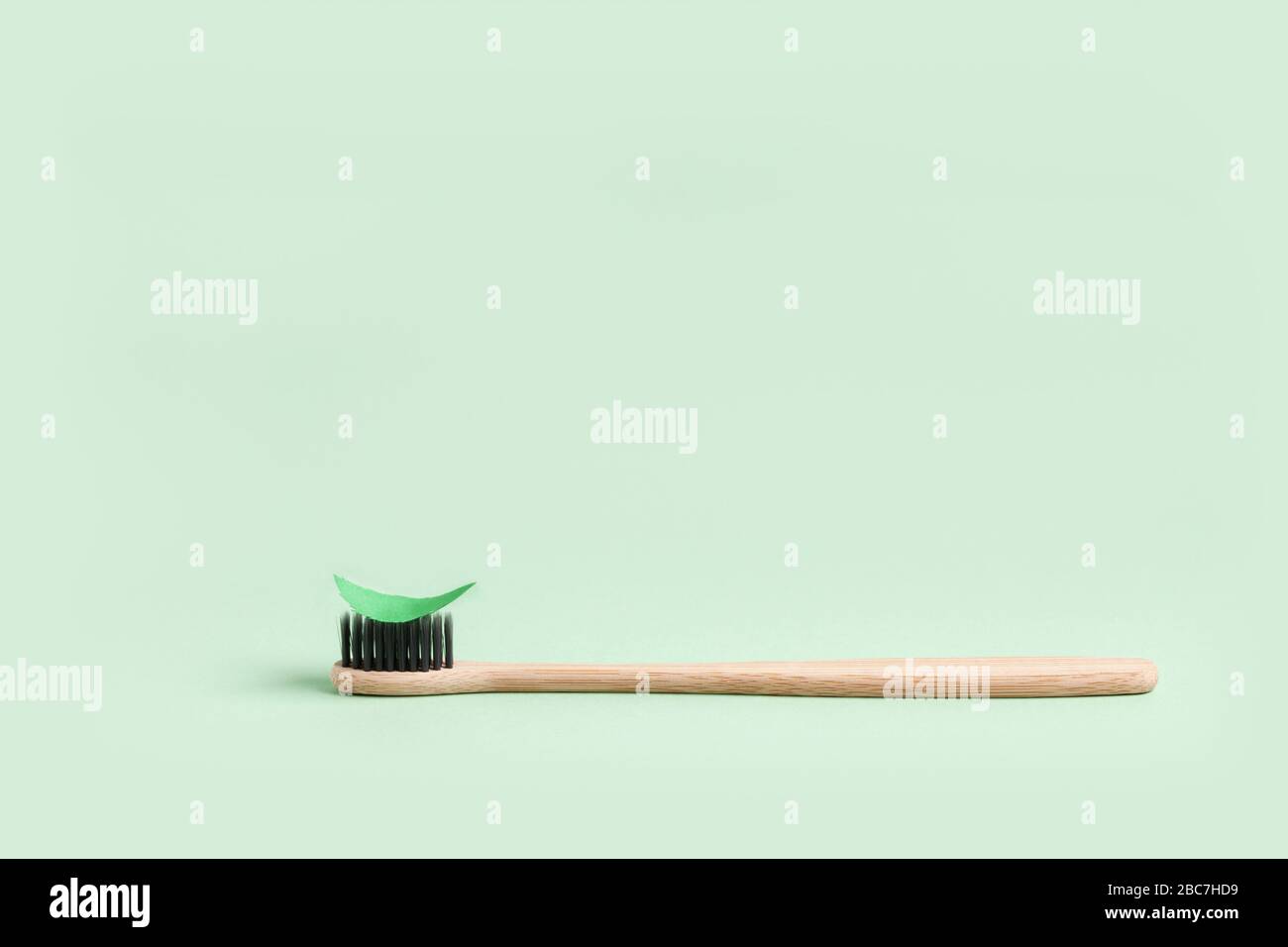 Minimalistic background with one wooden toothbrush and a mint paper ...