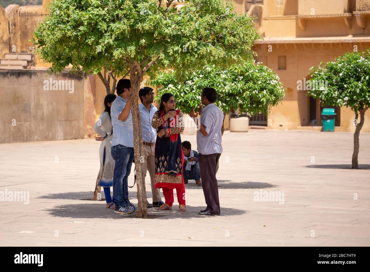 Group of locals finding shade under a tree during a hot summer day ...