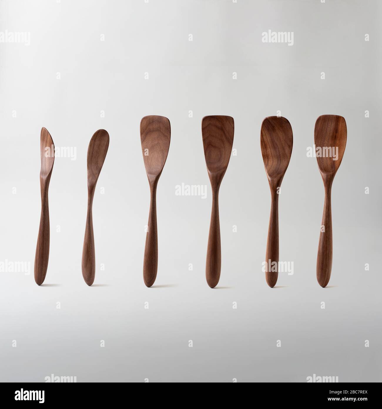 Handmade spatulas of walnut wood positioned in a studio against a white ...