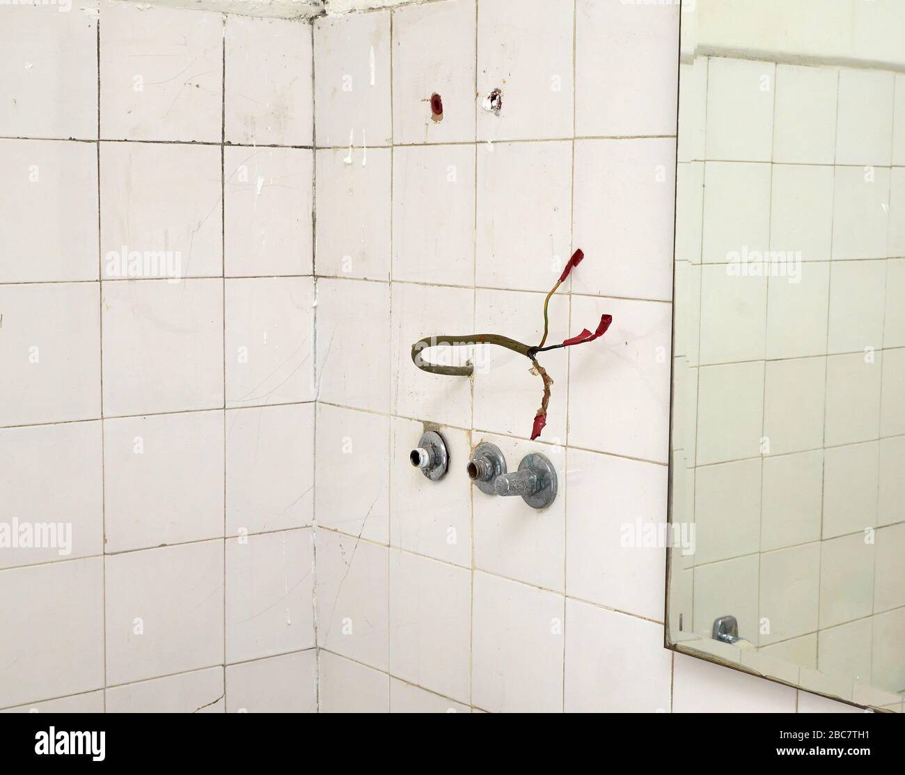 Bathroom with old white tiles and electric wires Stock Photo - Alamy