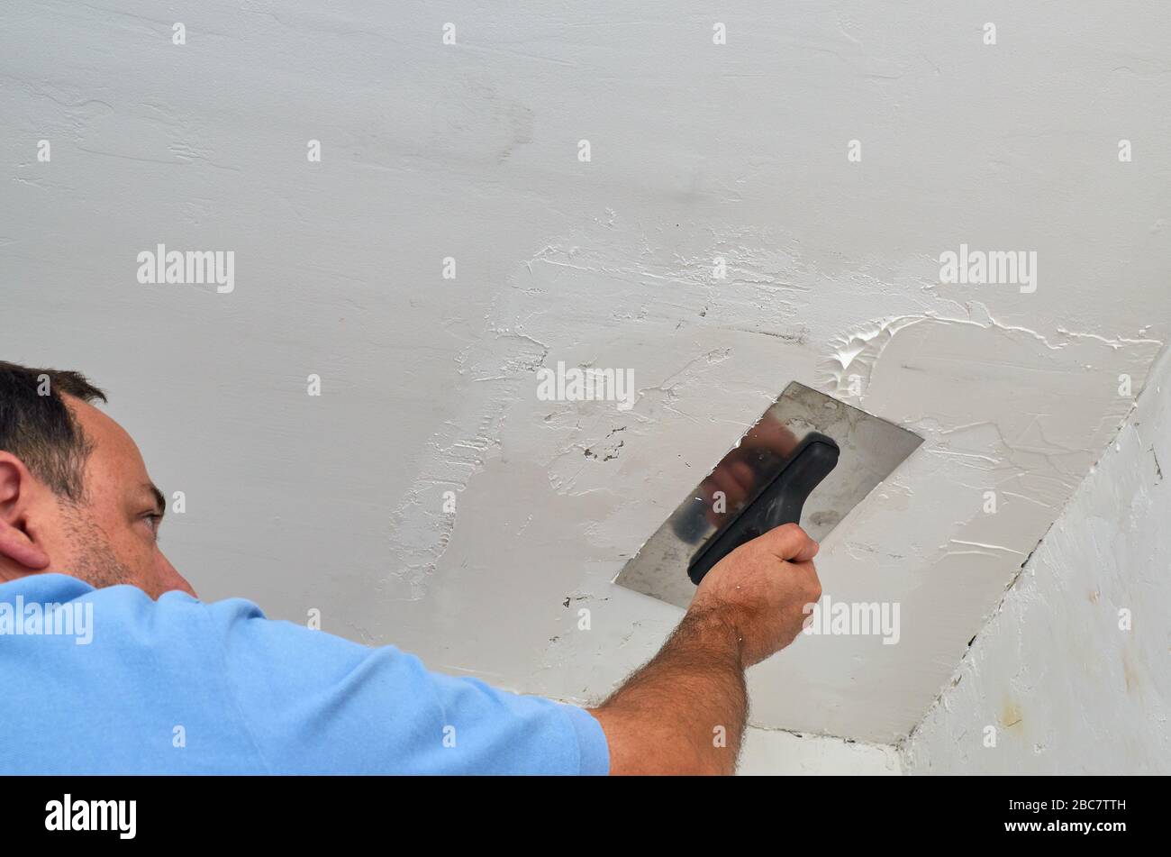 Man smoothing a ceiling with a trowel during renovating works Stock ...