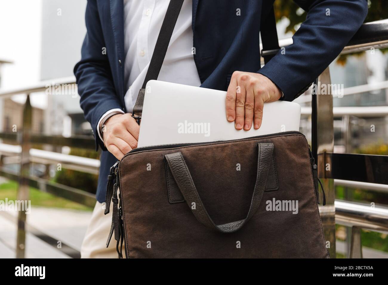 Close up of a man in formal wear taking his laptop out of the bag while ...
