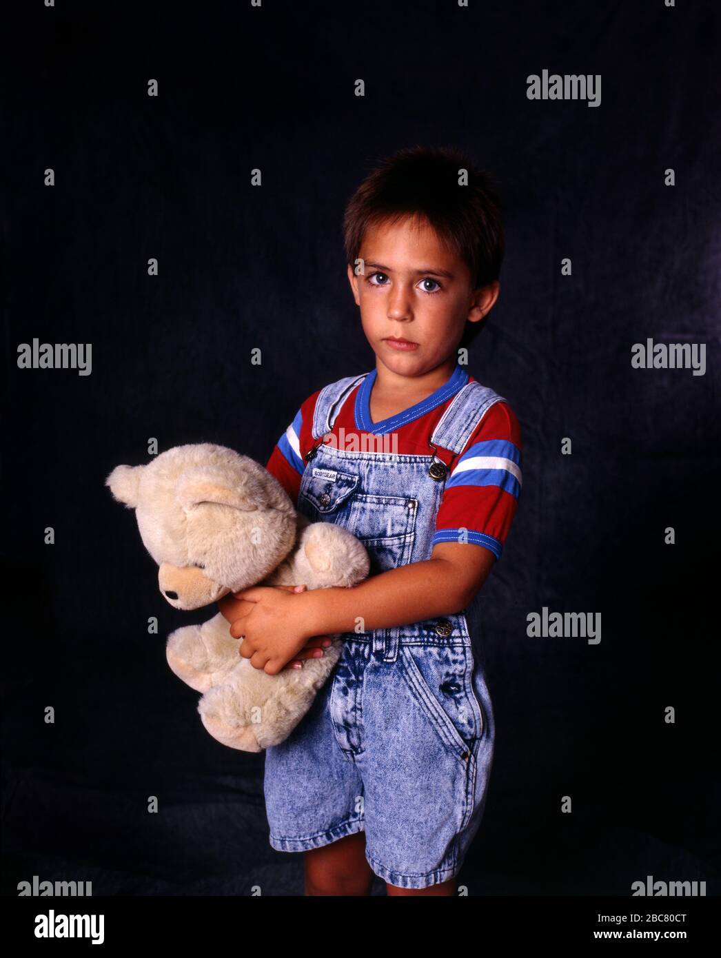Young boy with serious look holding teddy bear Stock Photo - Alamy