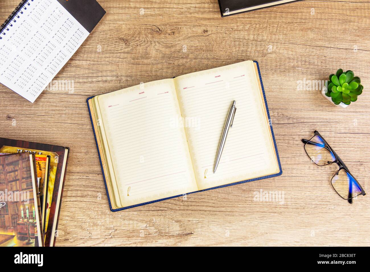 Flat lay with open vintage notebook, pen, glass, suculent, book stuck ...