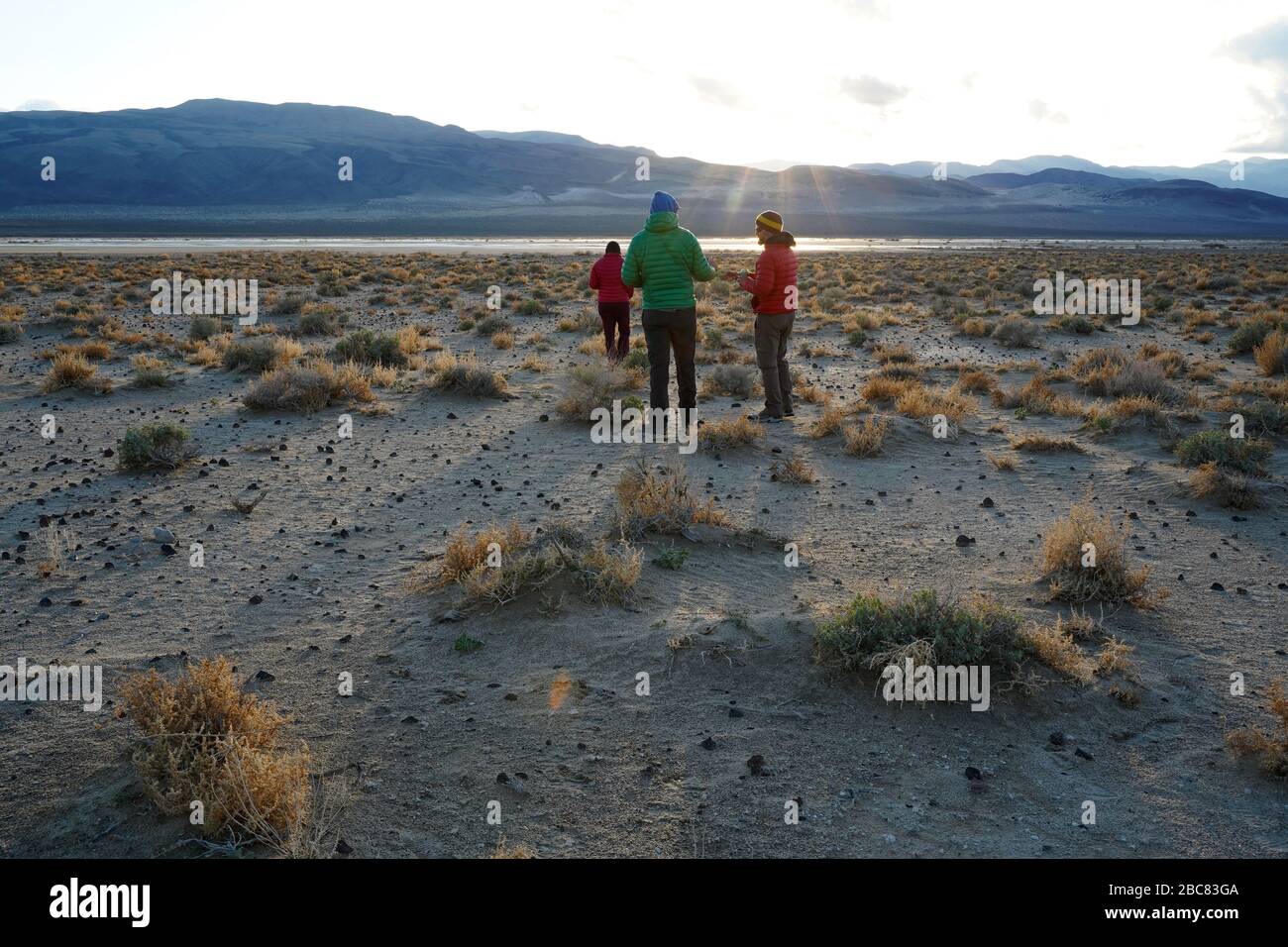 Three people hike through a desert landscape at sunset Stock Photo - Alamy