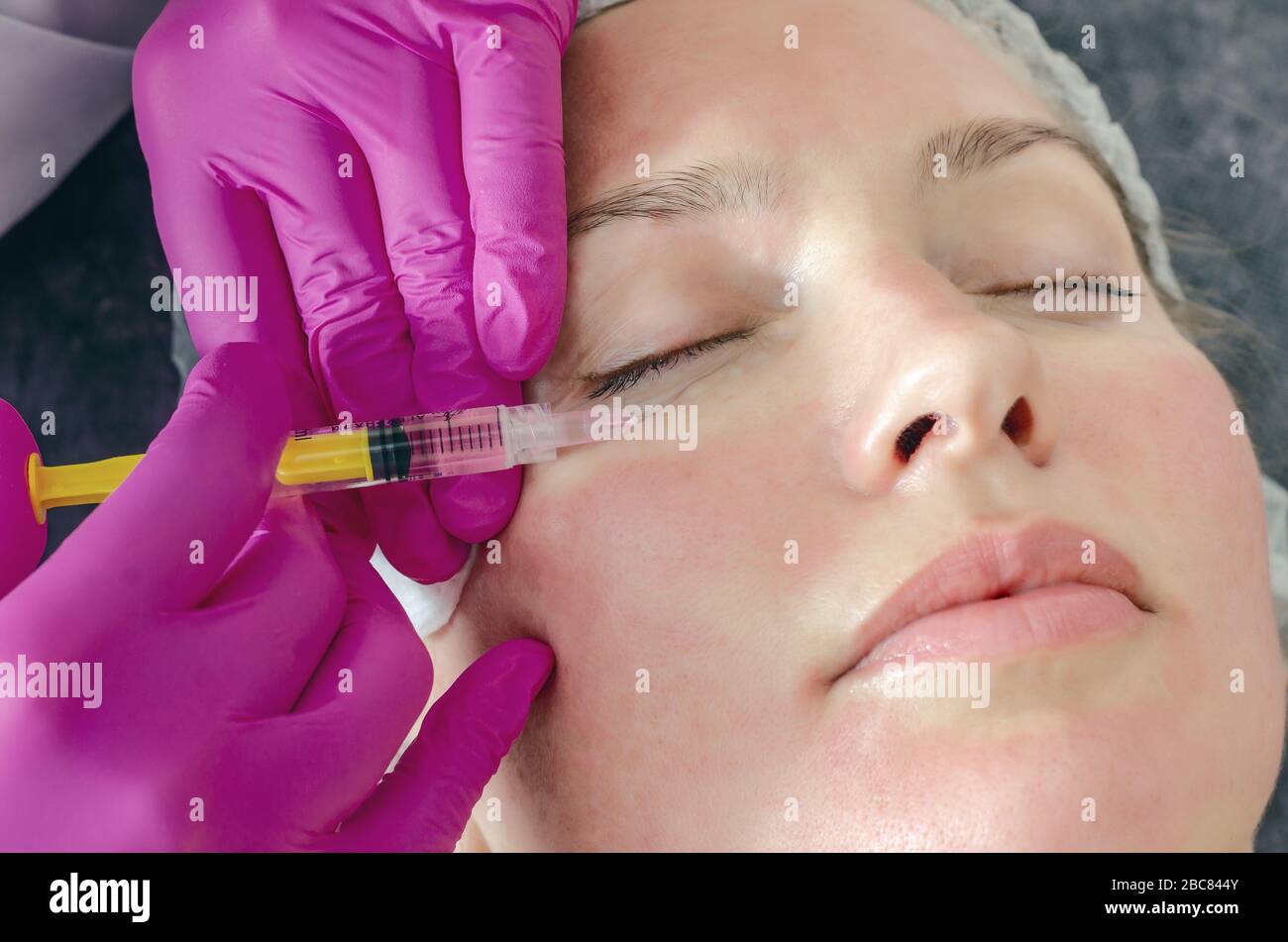 Woman face makes beauty injections around eyes, syringe, medicine ...