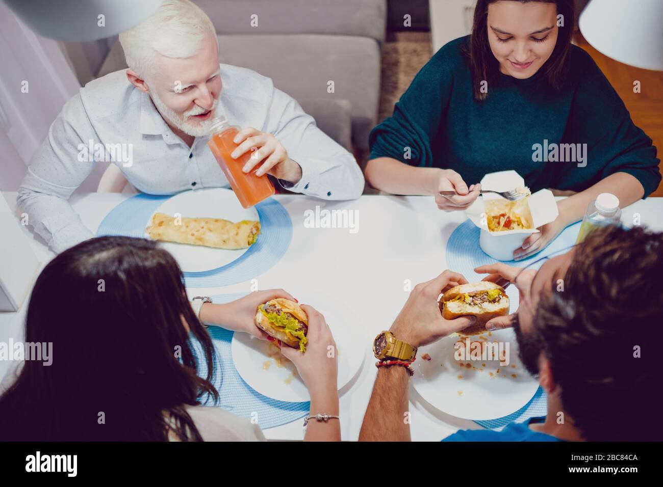 Friends smiling while eating fast food for a diner in the house Stock ...