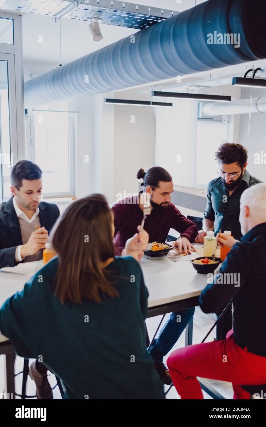 Serious coworkers having lunch at the table in the office Stock Photo ...