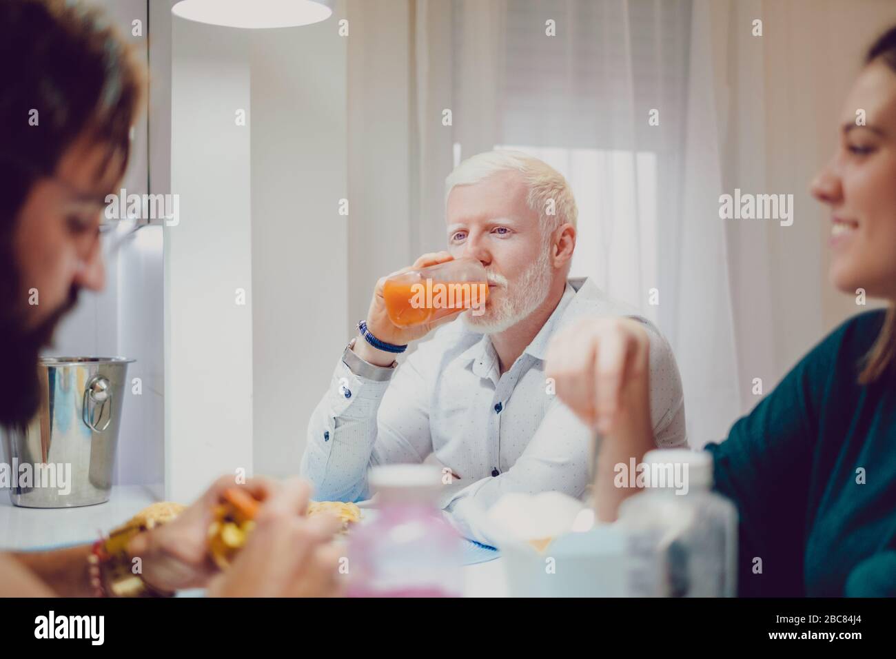 Handsome albino man drinking juice at the dinner with friends Stock ...