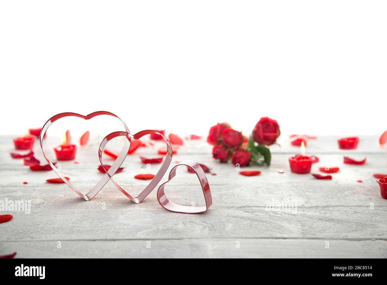 Red metal love hearts with fabric rose petals on a wood background ...