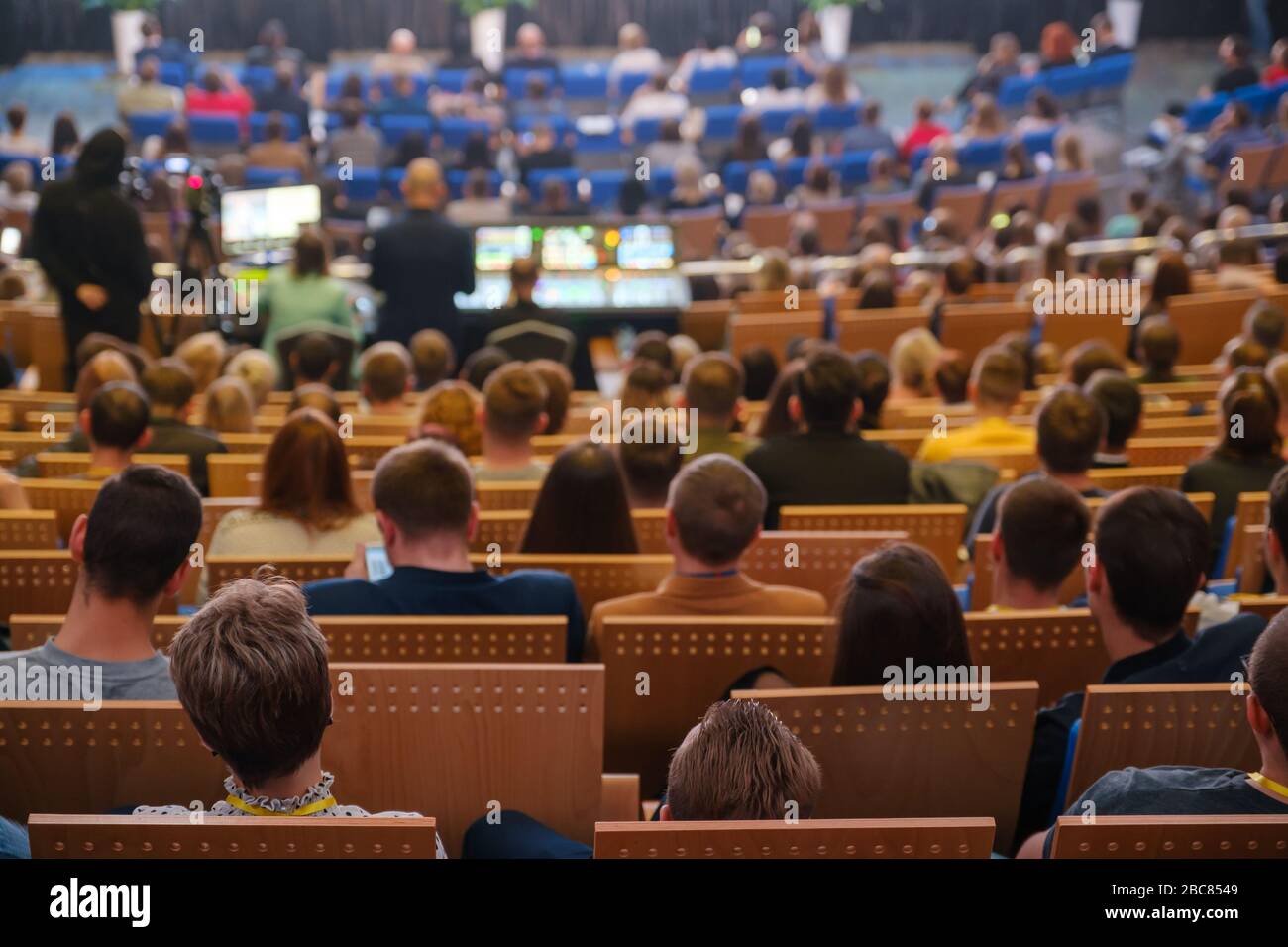 Business conference attendees sit and listen to lecturer, rear top view ...