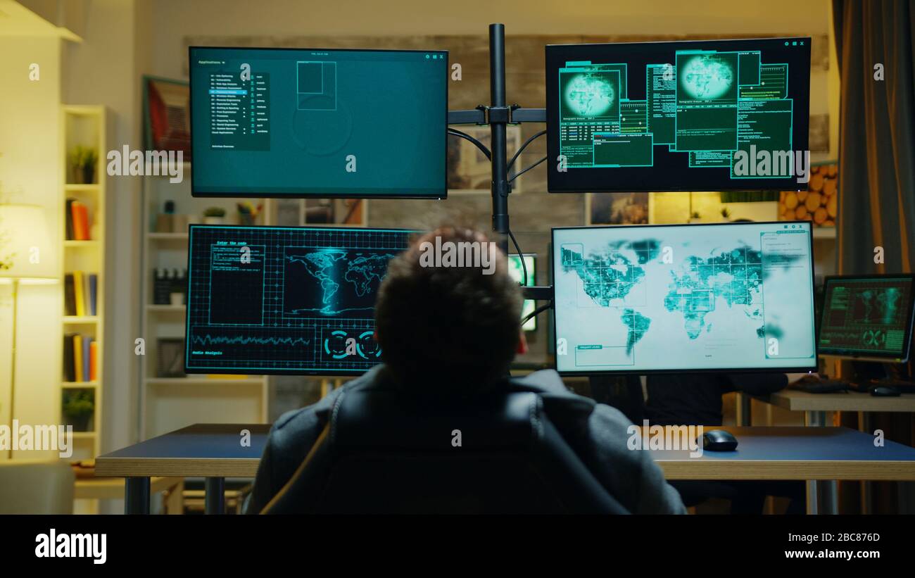 Hacker laying back on his chair while using powerfull computer to do ...