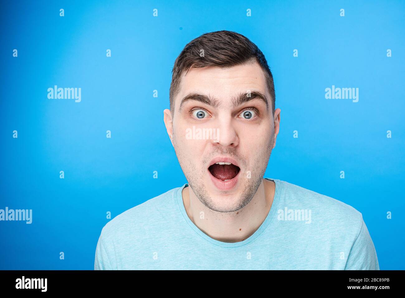 Surprised young guy is posing in studio Stock Photo - Alamy
