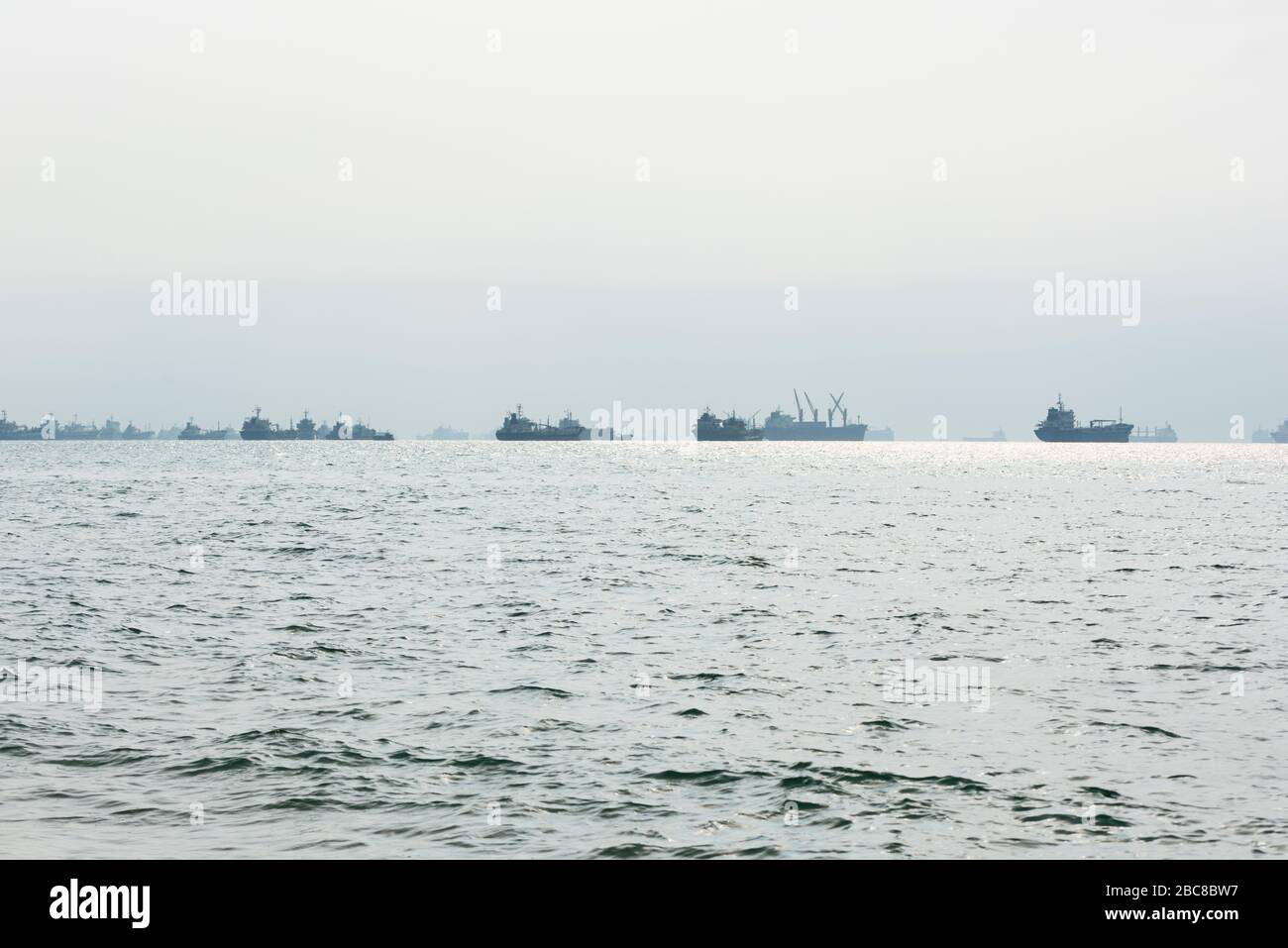 Cargo ships, oil tankers and bulk carriers anchored offshore along the ...