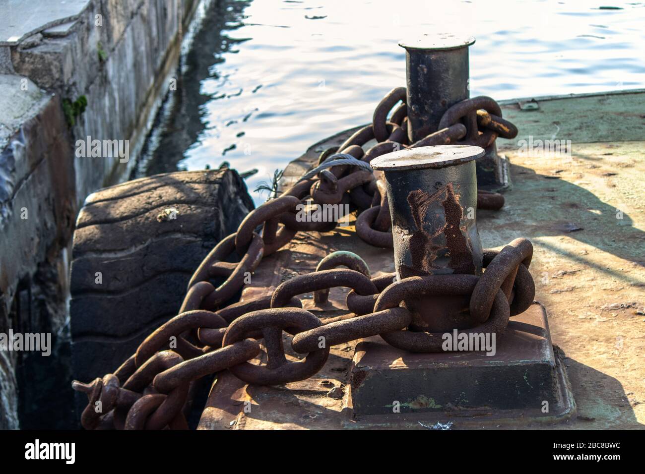 Iron rusty ropes are located on bitts close-up. Painted black Sunny day ...