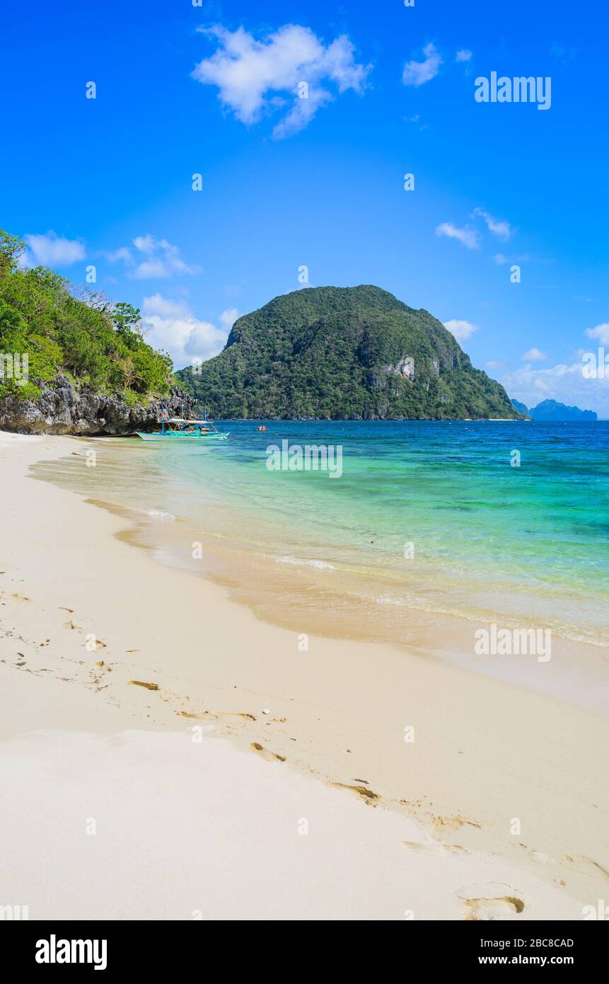 Sandy beach with an traditional banca boat in clear water, El Nido ...