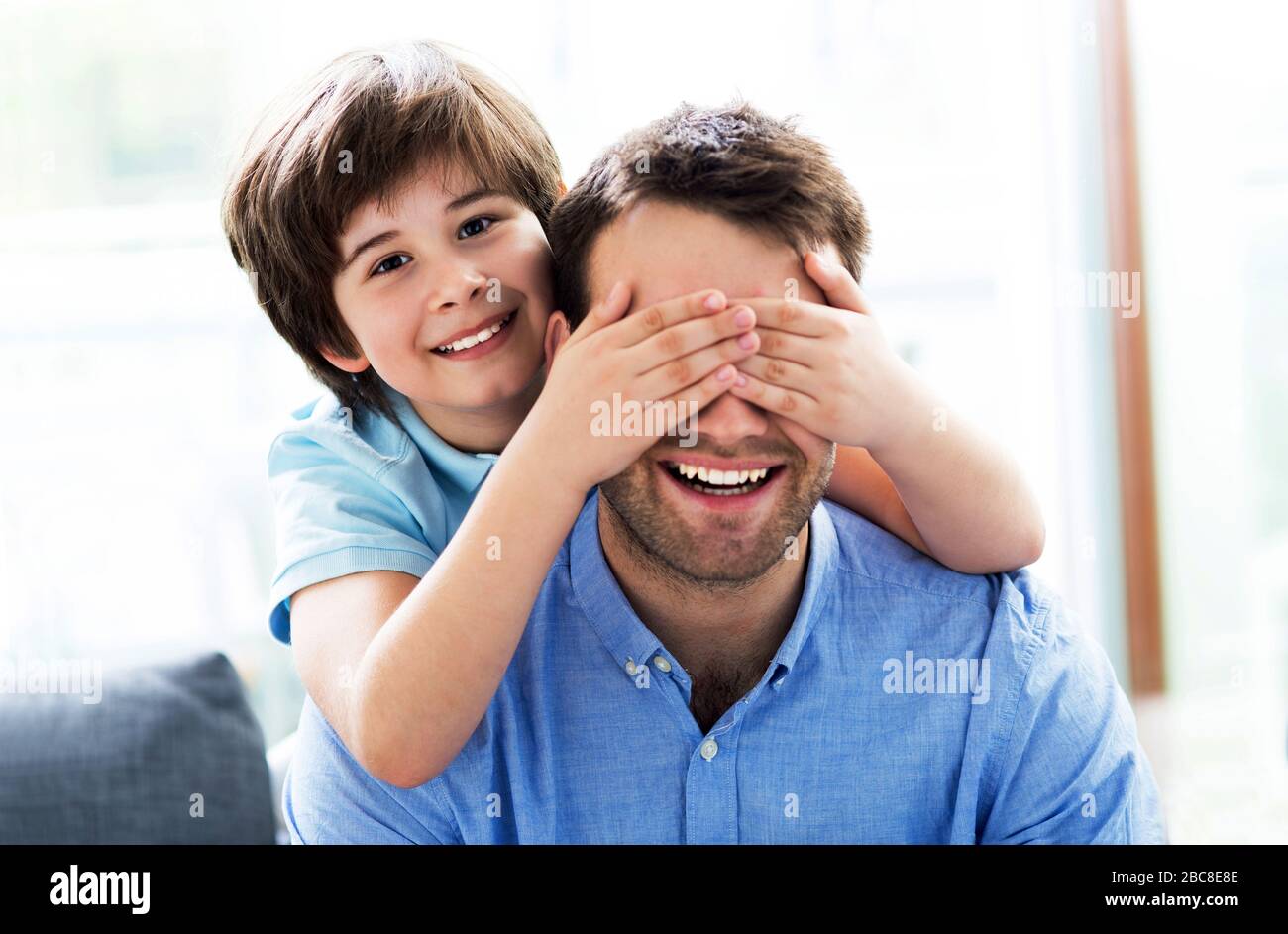 Boy covering father's eyes Stock Photo - Alamy