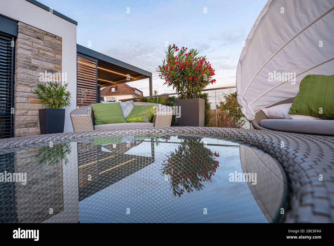 Lounge furniture on a modern terrace with reflection in glass table top ...