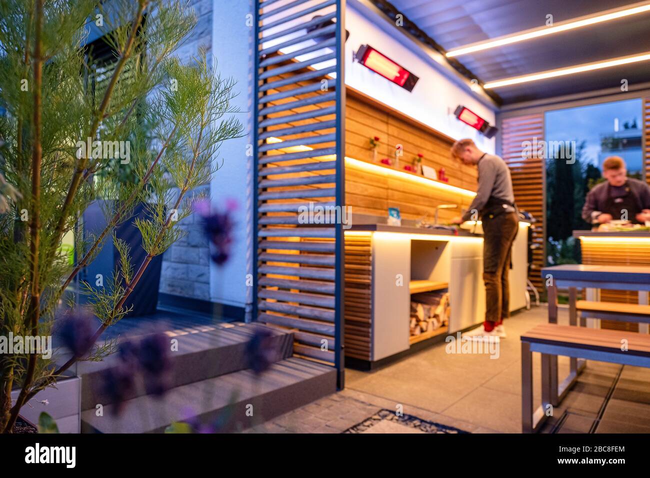 Young cooks in a modern outdoor kitchen at night on a terrace with ...