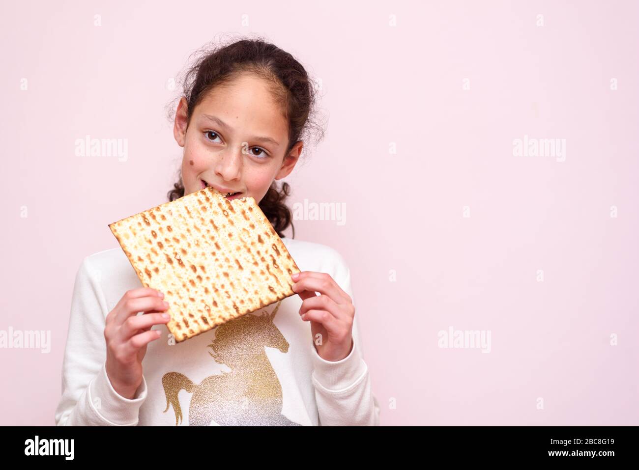 Portrait of the cute teenager girl holding matzah. Jewish child eating ...